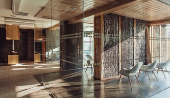 Um interior moderno com divisória de vidro, teto de madeira e cadeiras contemporâneas.