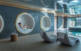 Uma área de spa moderna com espelhos circulares, piscina e espreguiçadeiras.