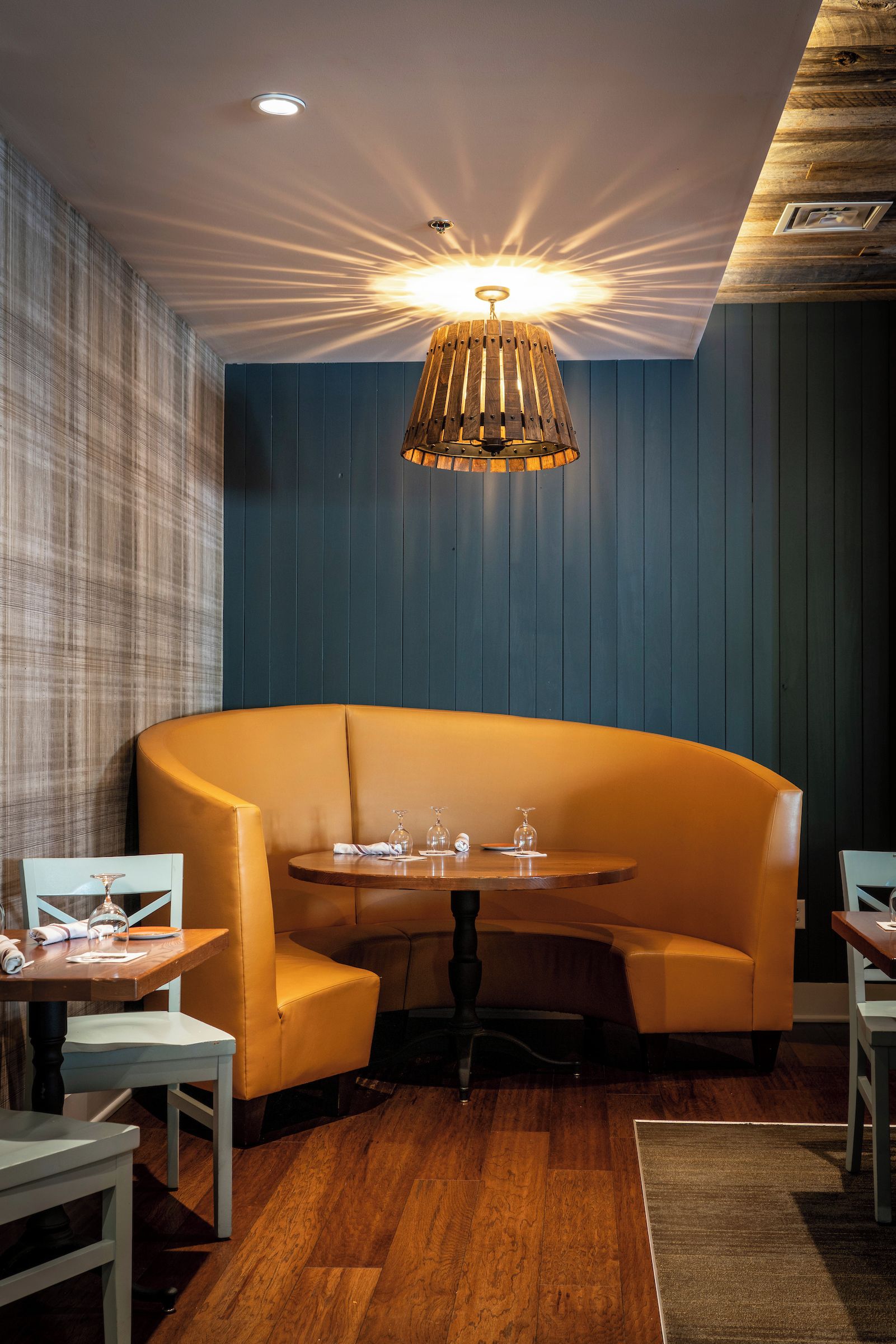 Um espaço de estar acolhedor com assentos, uma mesa redonda, um candelabro singular e uma parede com padrão.