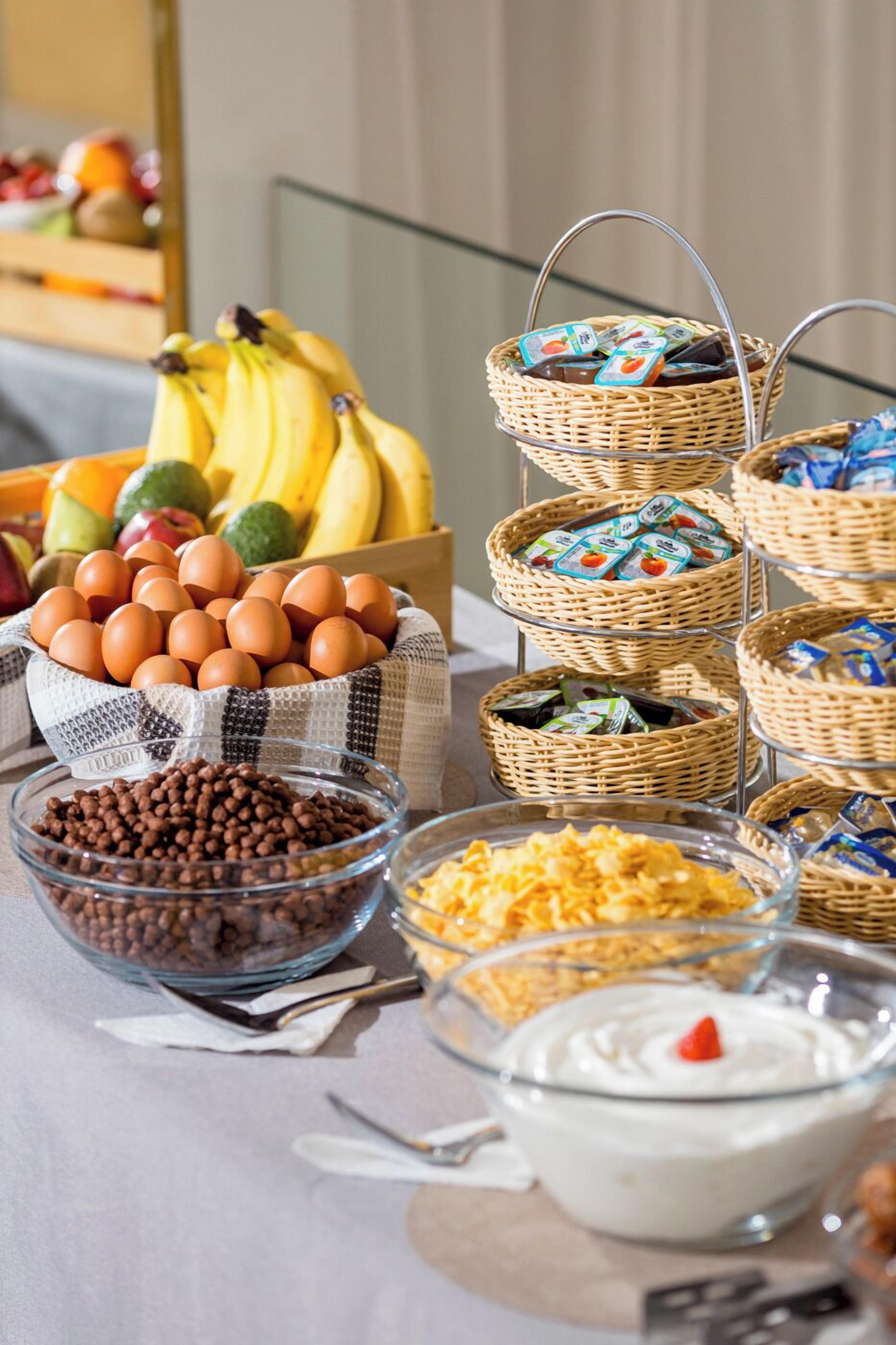Mesa de buffet com diversos alimentos, incluindo ovos, bananas e iogurte.