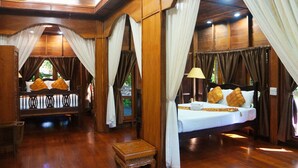 Quarto de madeira com cama, cortinas e uma pequena mesa.