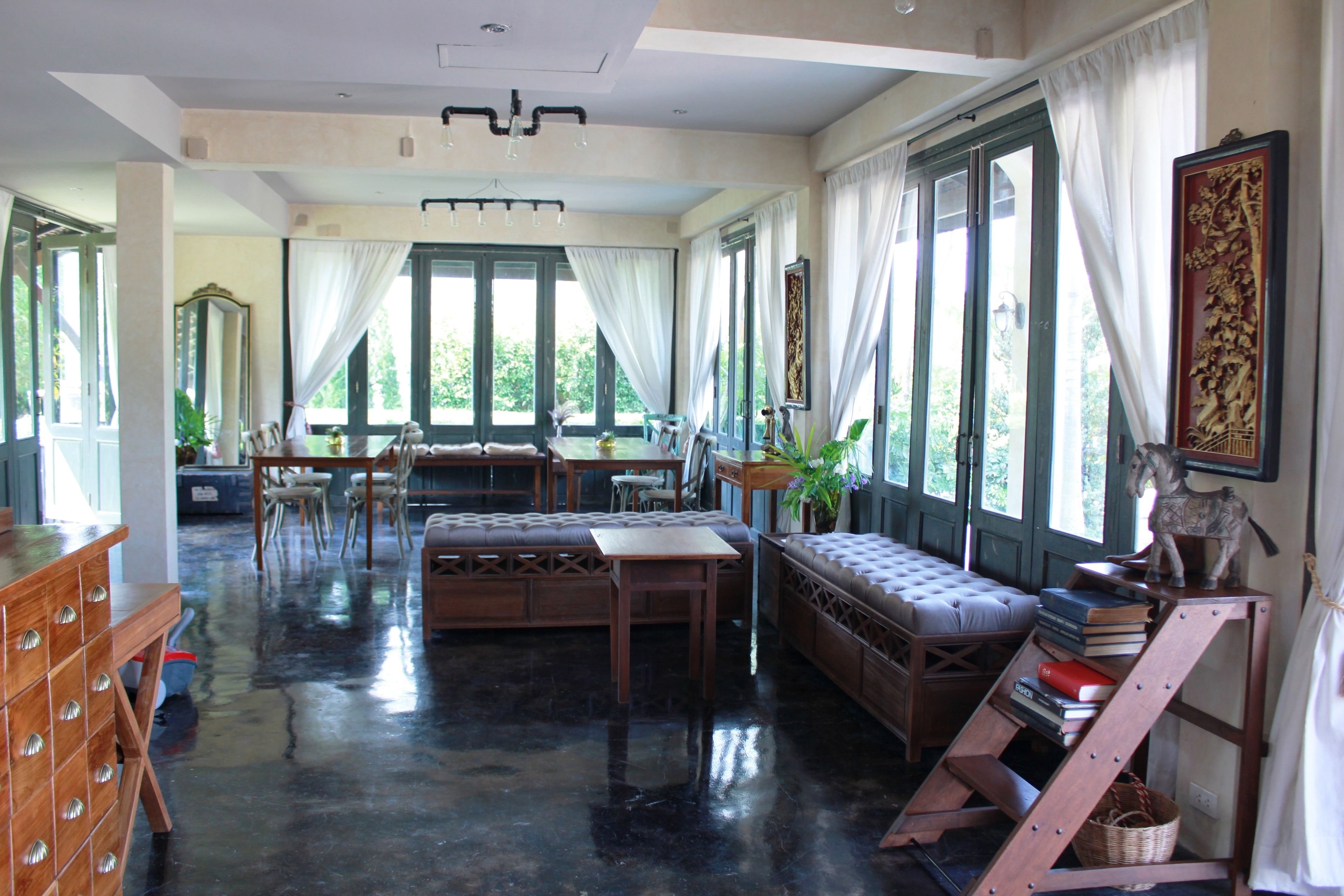 Um quarto amplo com uma grande janela, uma mesa de madeira, um banco acolchoado e uma estante de livros.