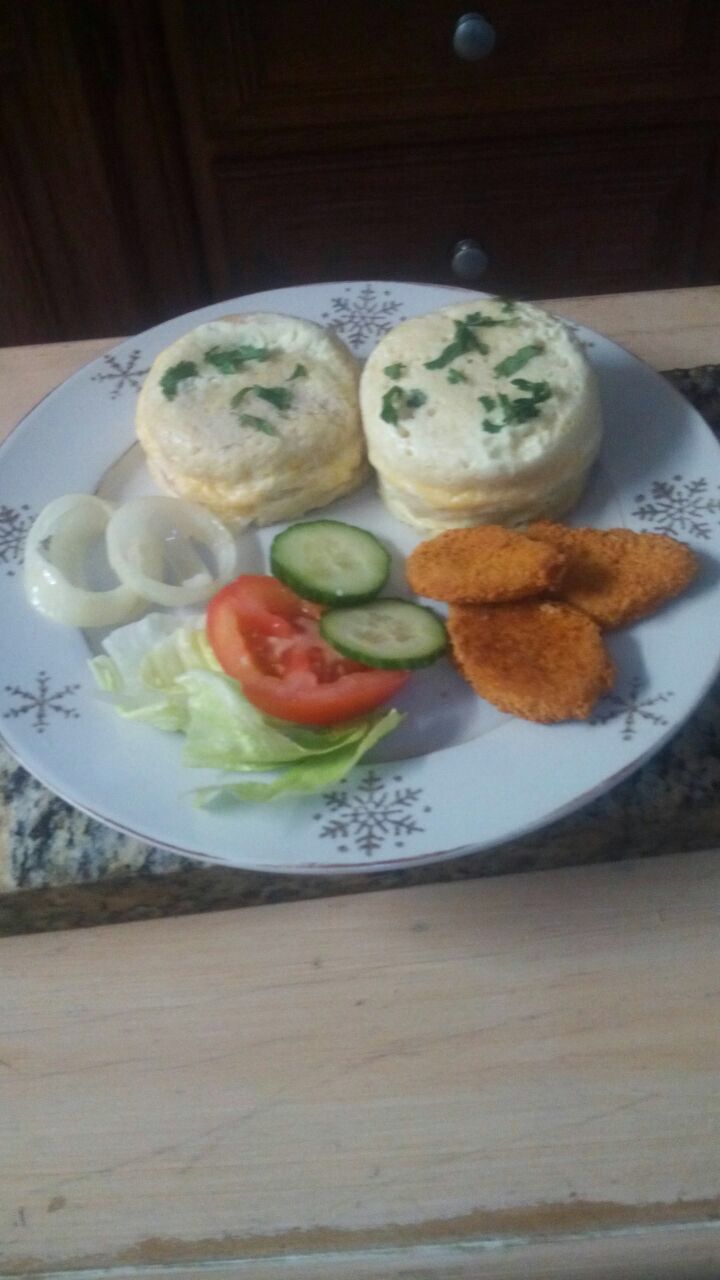 Um prato com dois biscoitos, uma salada e alguns petiscos empanados.