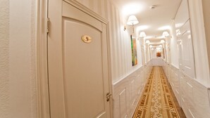 Um corredor de hotel com piso coberto por carpete, paredes brancas e portas numeradas 9.