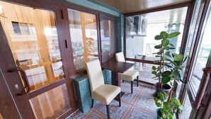 Uma sala de jantar com mesa e cadeiras de madeira, piso estampado e um vaso com planta.