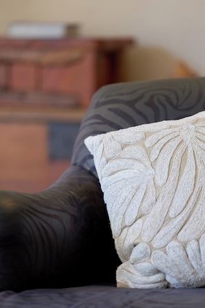 Uma cama com travesseiro escuro e um travesseiro decorativo com padrão floral.