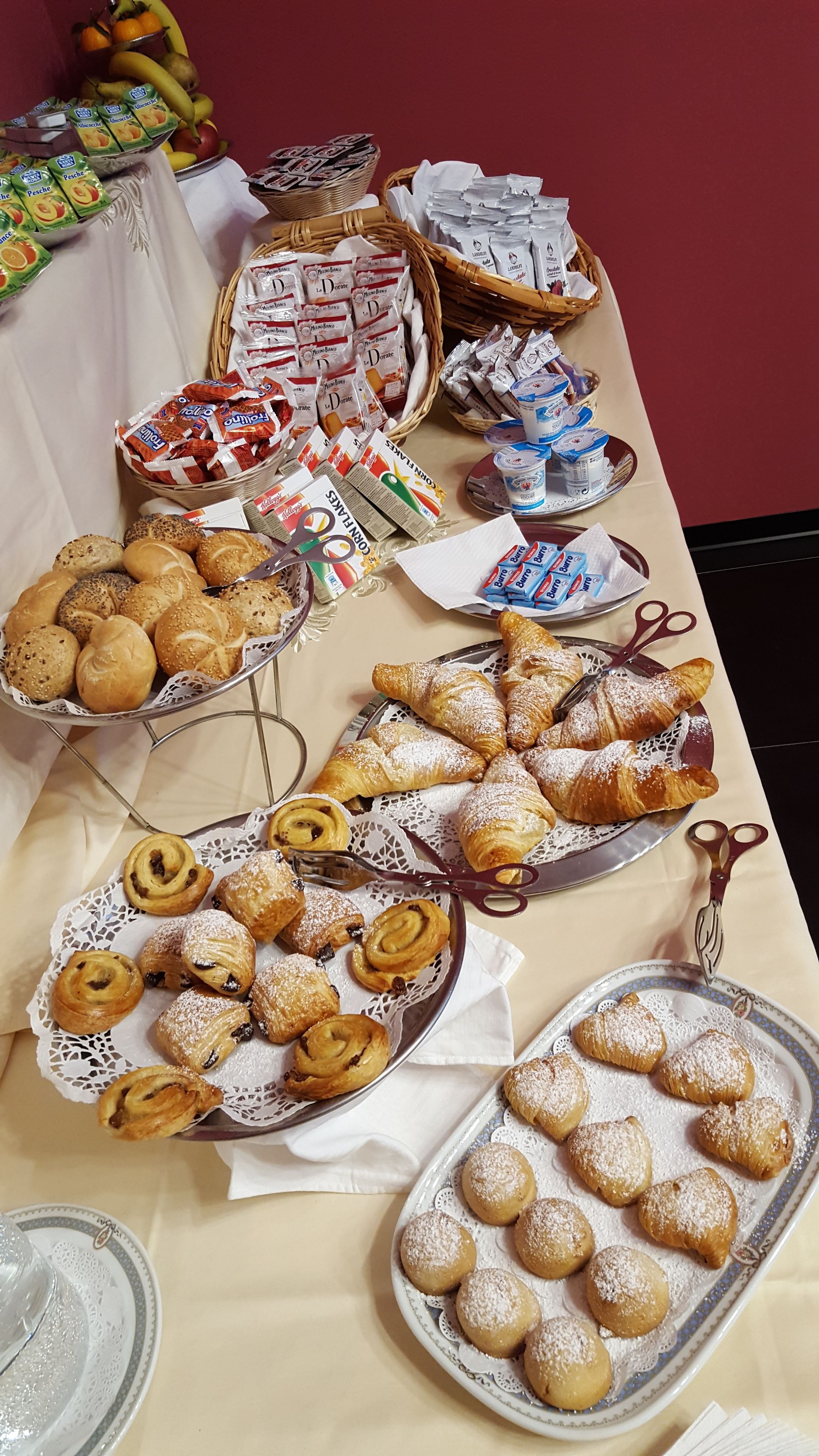Uma mesa de buffet com diversos doces, pães e produtos embalados.