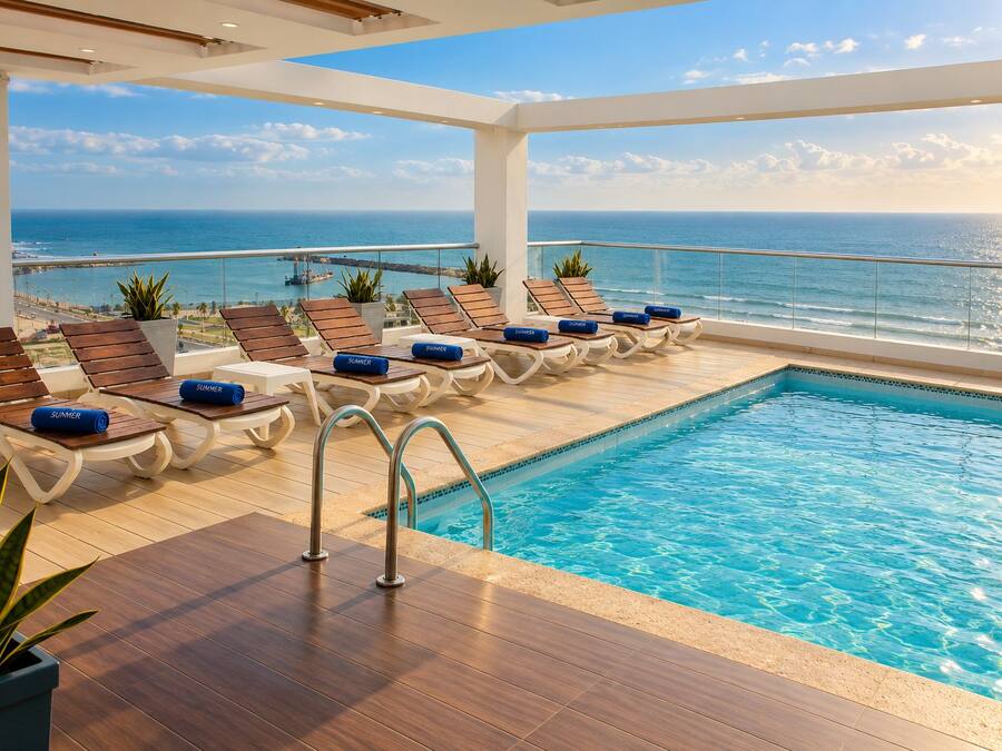 Área de piscina com espreguiçadeiras e vista para o oceano.