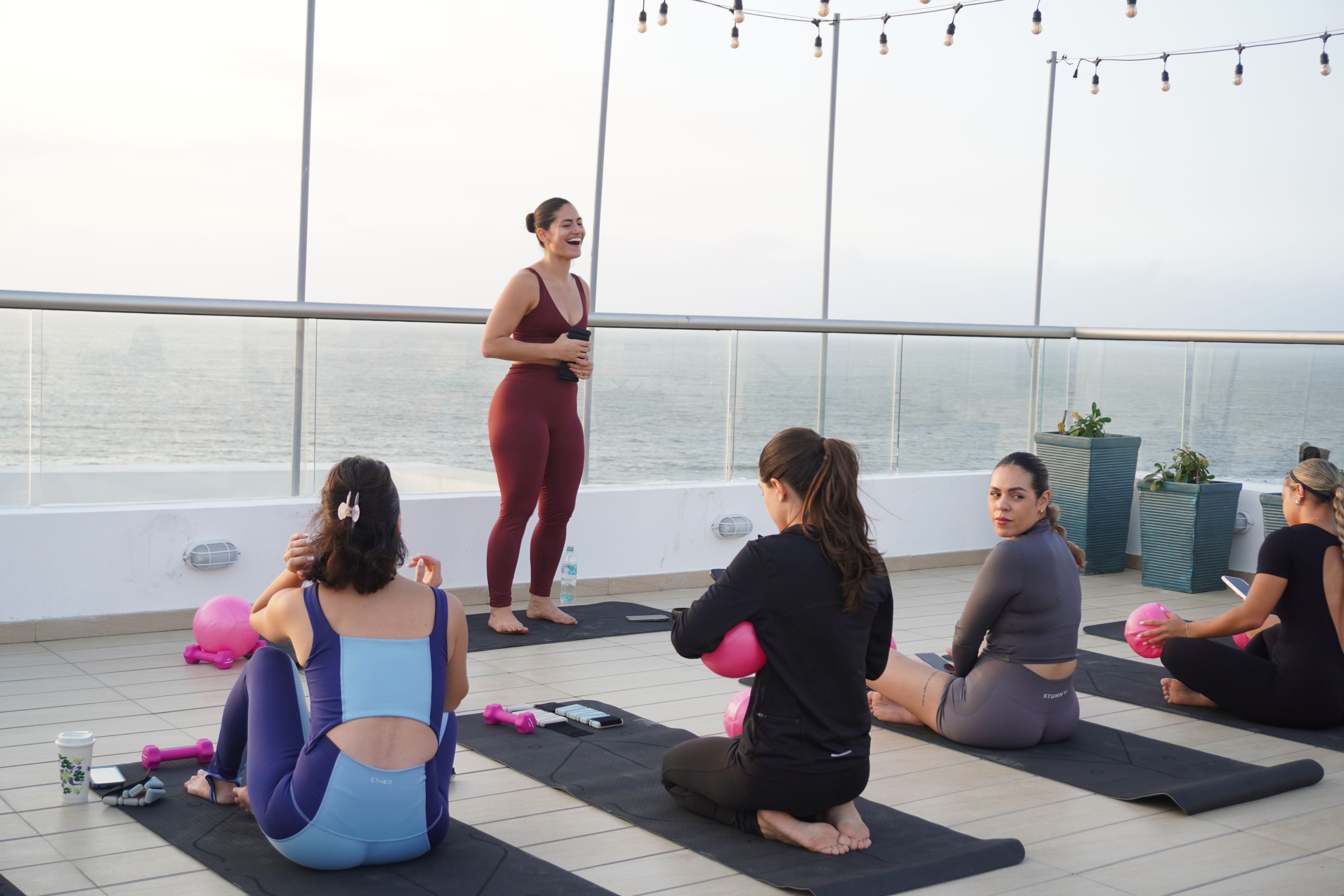 Um grupo de pessoas em um terraço, praticando yoga com vista para o mar.