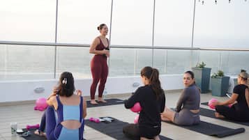 Um grupo de pessoas em um terraço, praticando yoga com vista para o mar.
