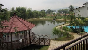 Um gazebo com telhado de cerâmica, com vista para um lago e uma piscina.