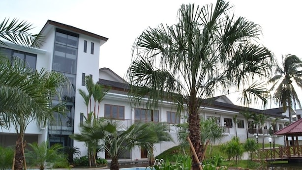 Um hotel moderno com piscina rodeada por palmeiras e vegetação exuberante.