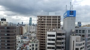 Paisagem urbana com diversos edifícios, incluindo um letreiro Shoko bem visível em uma construção.
