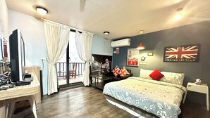 Quarto de hotel com cama, escrivaninha, televisão, varanda e parede com a bandeira do Reino Unido.