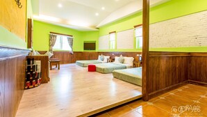 Quarto de hotel com piso de madeira, paredes verdes, parede de tijolos e uma cama grande com almofadas.