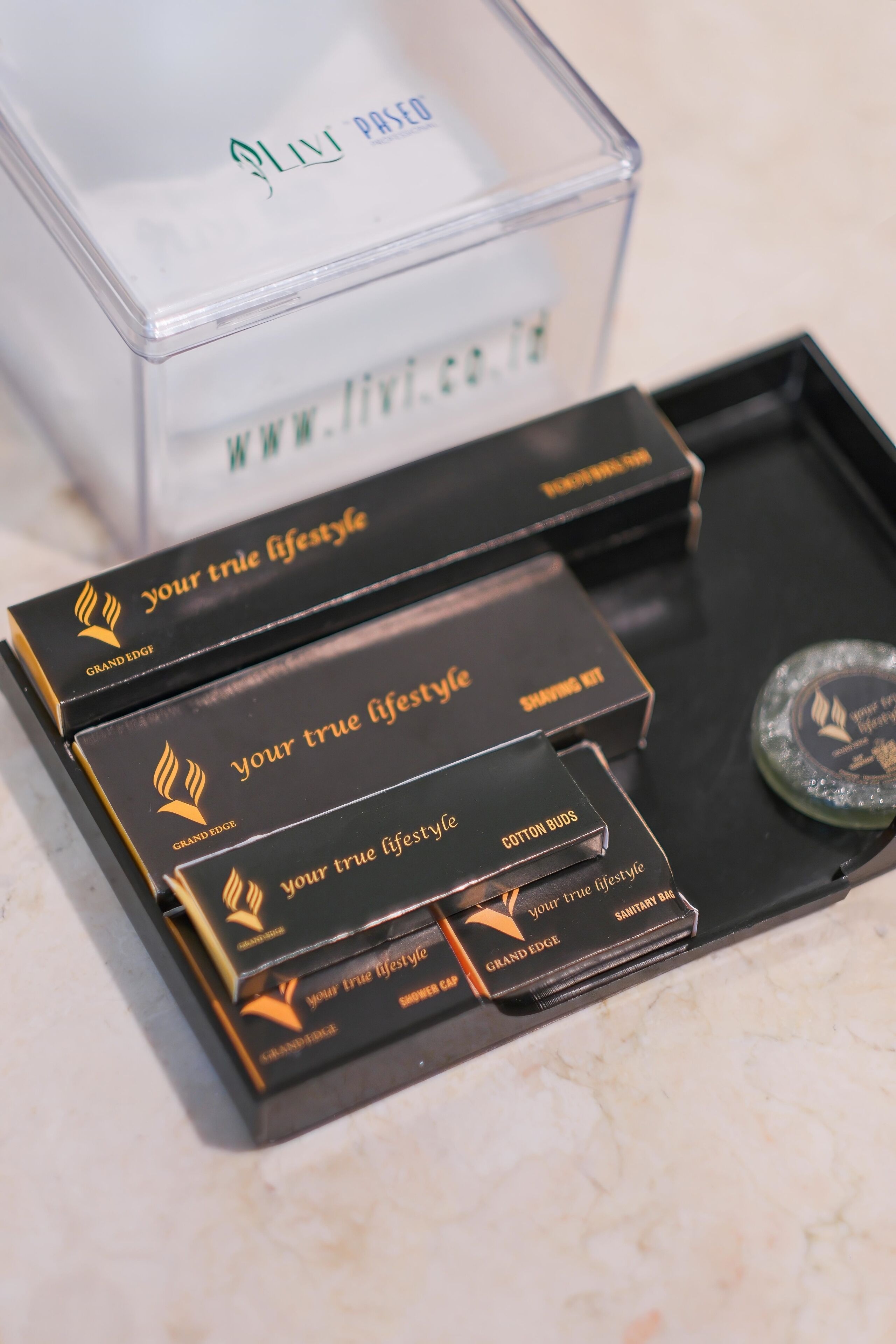 Conjunto de caixas pretas com texto dourado e um logotipo, dispostas numa bandeja.