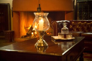 Um quarto aconchegante com lareira, um sofá de couro e uma mesa com vela e objeto decorativo.