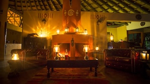 Um quarto bem iluminado, com teto de madeira, lareira central e dois sofás.