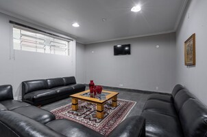 Uma sala de estar moderna com um sofá de couro preto, uma mesa de centro de madeira e um tapete estampado.