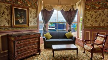 Quarto com sofá escuro, cómoda de madeira e tapete estampado.