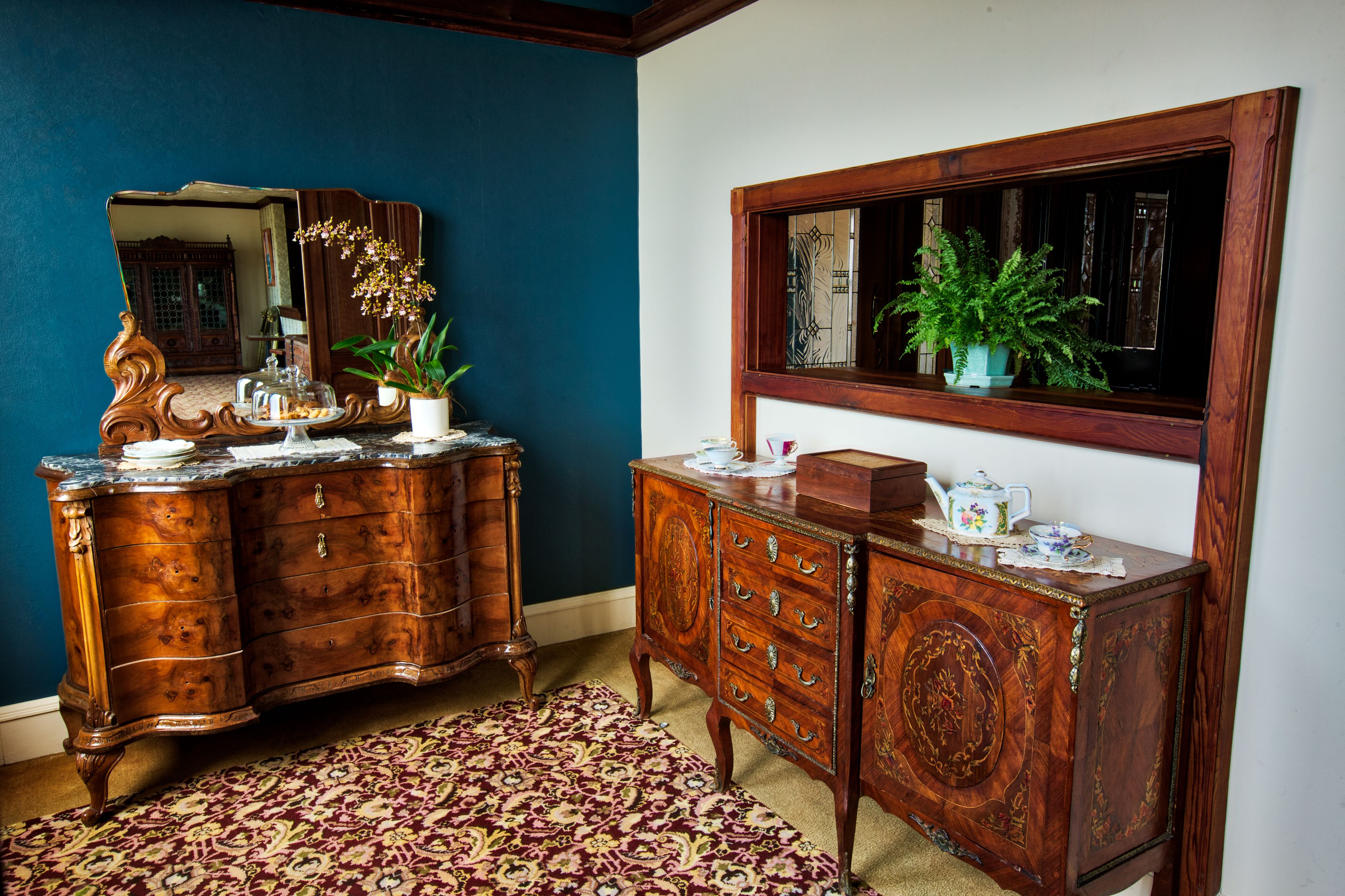 Quarto com cômoda de madeira, espelho e janela com plantas.