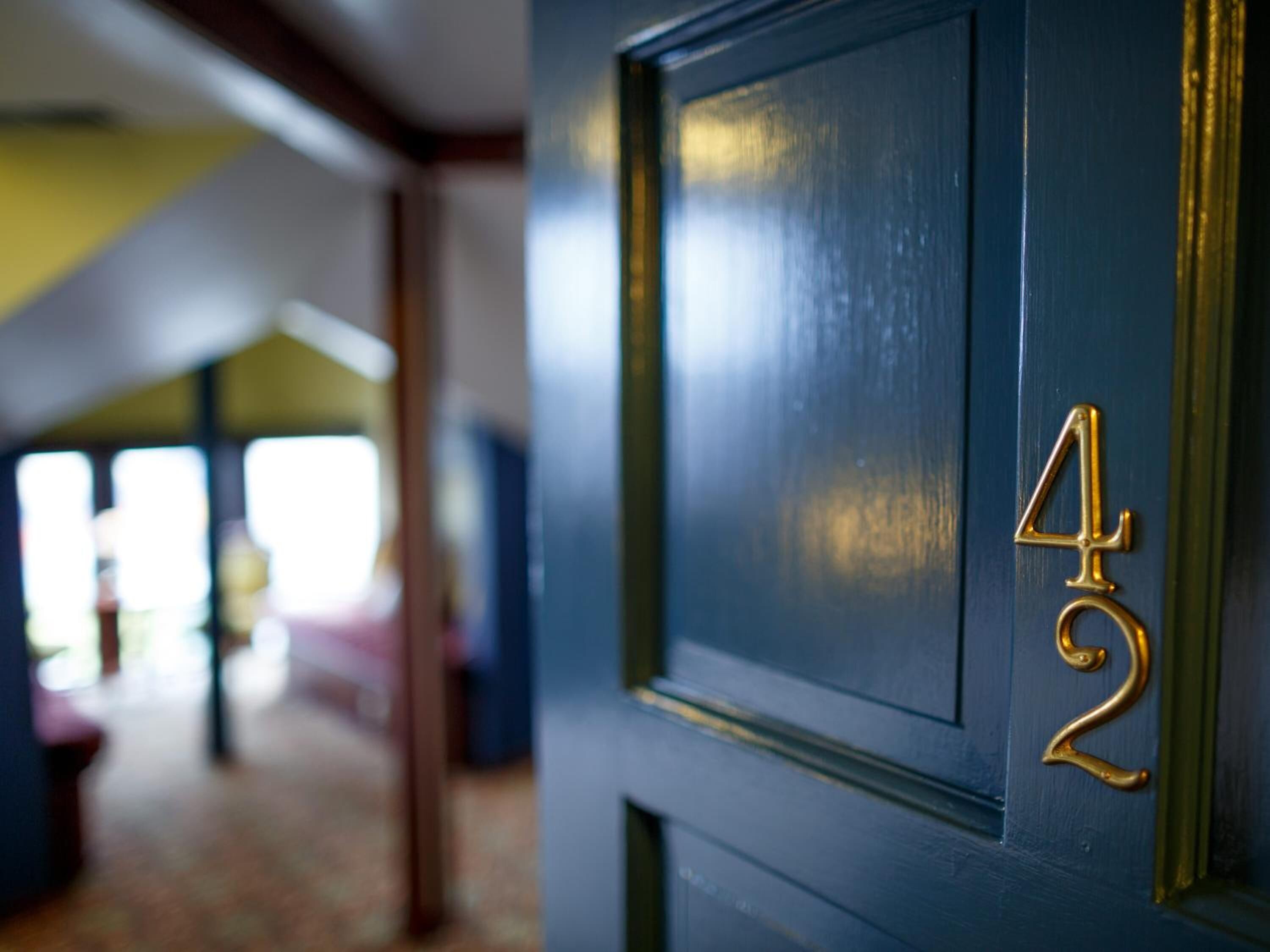 Um close-up de uma porta azul escura com o número 42 em dourado.