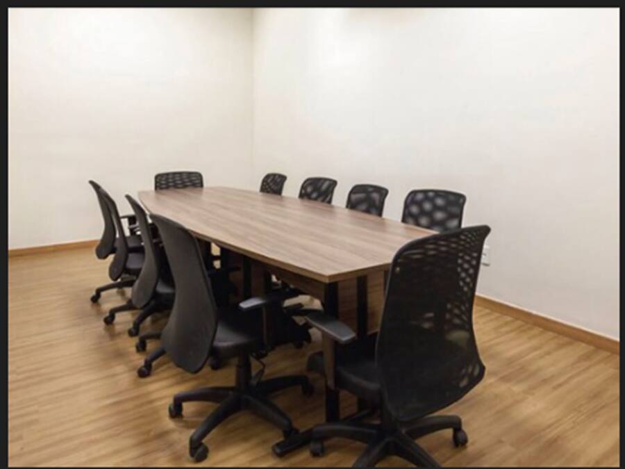 Uma sala de conferência com uma mesa comprida e seis cadeiras de escritório pretas.