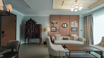 Quarto de hotel moderno com sofás, um armário de madeira, uma mesa de jantar e um candelabro.