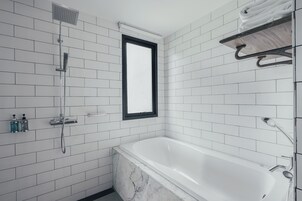 Um banheiro moderno com paredes revestidas de azulejos brancos, uma banheira, um chuveiro e uma janela.