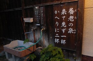 Uma porta de madeira com texto em japonês e uma pia externa pequena com mangueira.