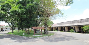Um edifício com varanda coberta e um pequeno jardim com um gazebo.