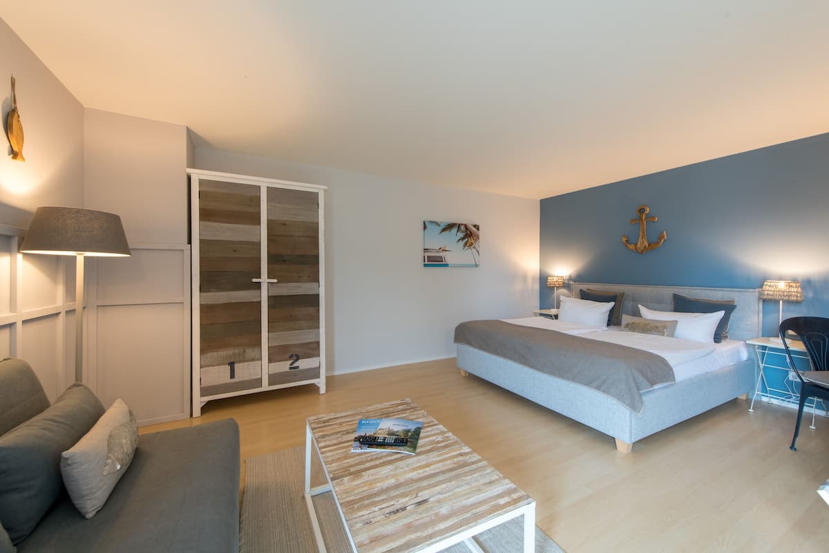 Quarto moderno com cama, sofá, mesa de centro, guarda-roupa e escrivaninha com cadeira.