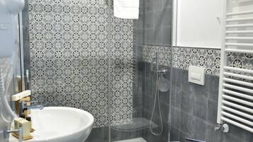 Uma casa de banho moderna com chuveiro, sanita, bidé e lavatório.