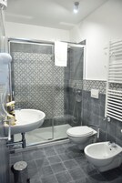 Uma casa de banho moderna com chuveiro, sanita, bidé e lavatório.