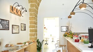 Uma cozinha com parede de pedra, armários de madeira e bancada de café da manhã com frutas e doces.