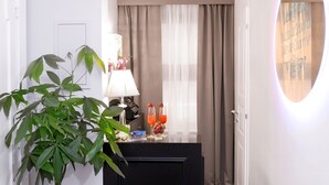 Um quarto com uma escrivaninha, uma luminária, um vaso de planta e uma janela com cortinas.