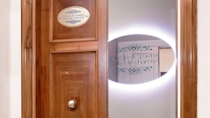 Uma porta de madeira com uma placa exibindo "Piazza di Spagna Suite de Charme" e um tapete de entrada com o mesmo texto.