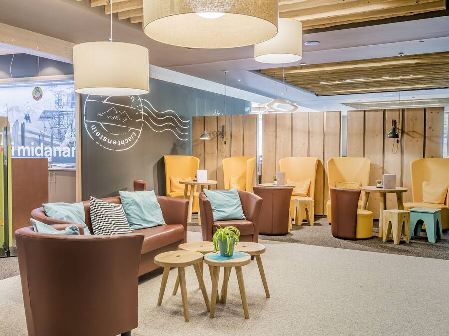 Uma área de estar moderna com sofás de couro, mesas de madeira e luminárias pendentes.