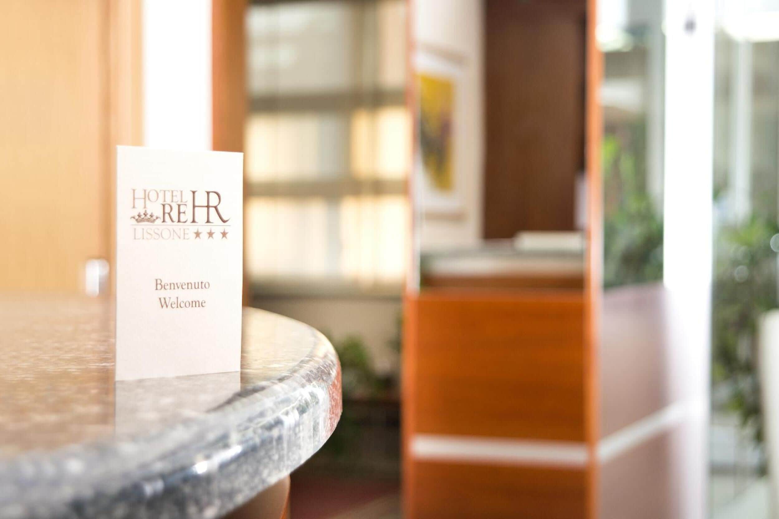 Cartão de boas-vindas do hotel sobre uma mesa de mármore, com fundo desfocado de mobiliário de madeira e uma janela.