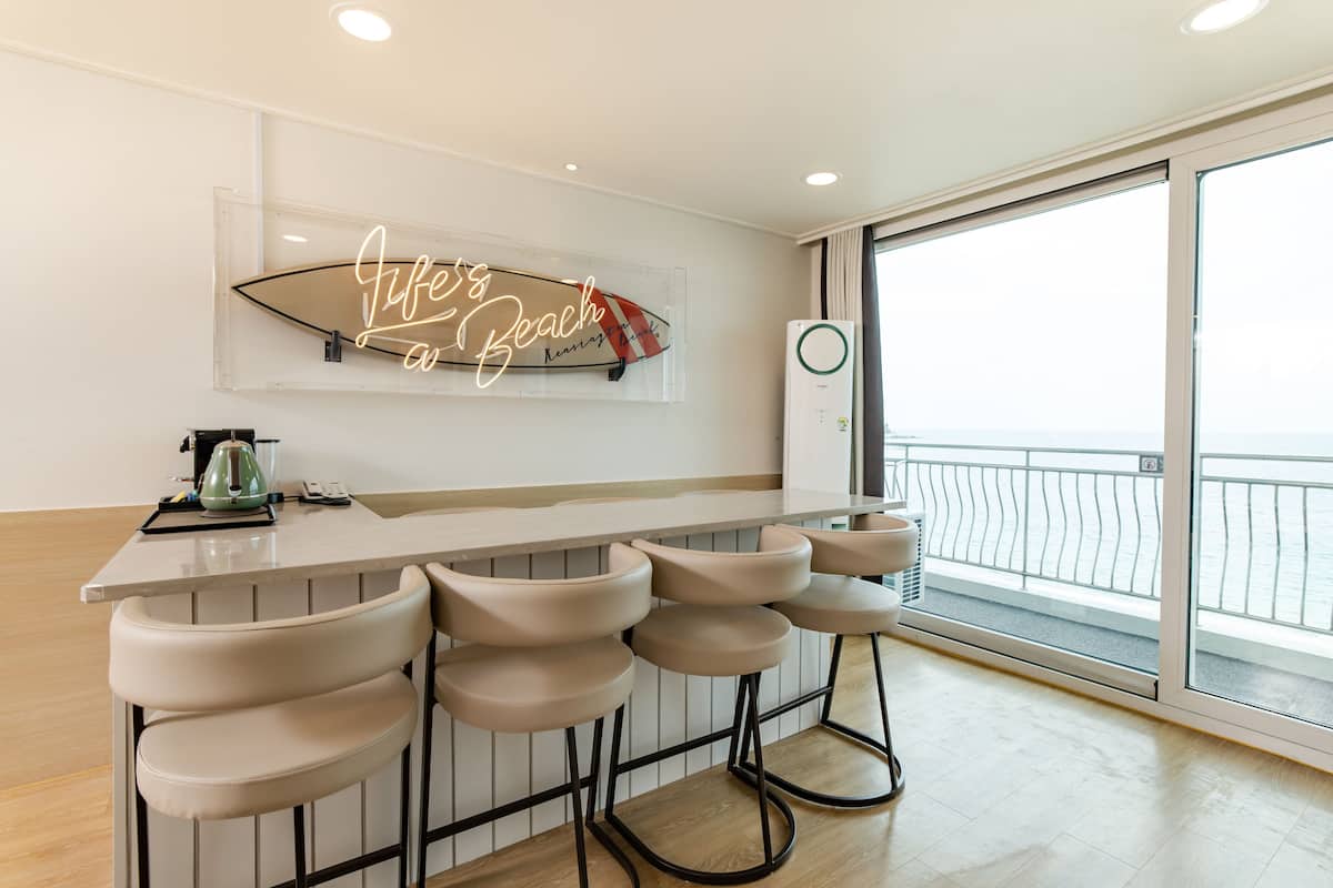 Cozinha moderna com área de bar, um letreiro de neon e vista para o mar.