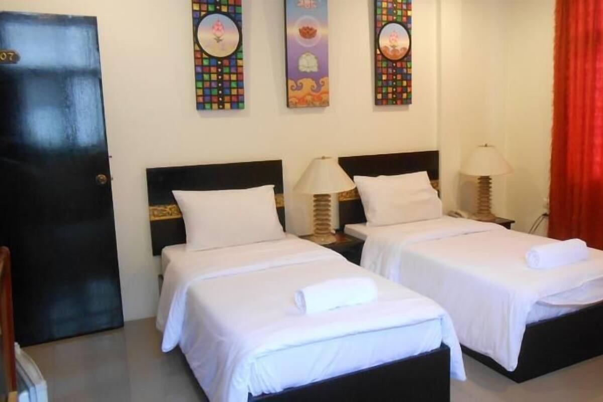 Quarto de hotel com duas camas, uma porta preta e três obras de arte na parede.
