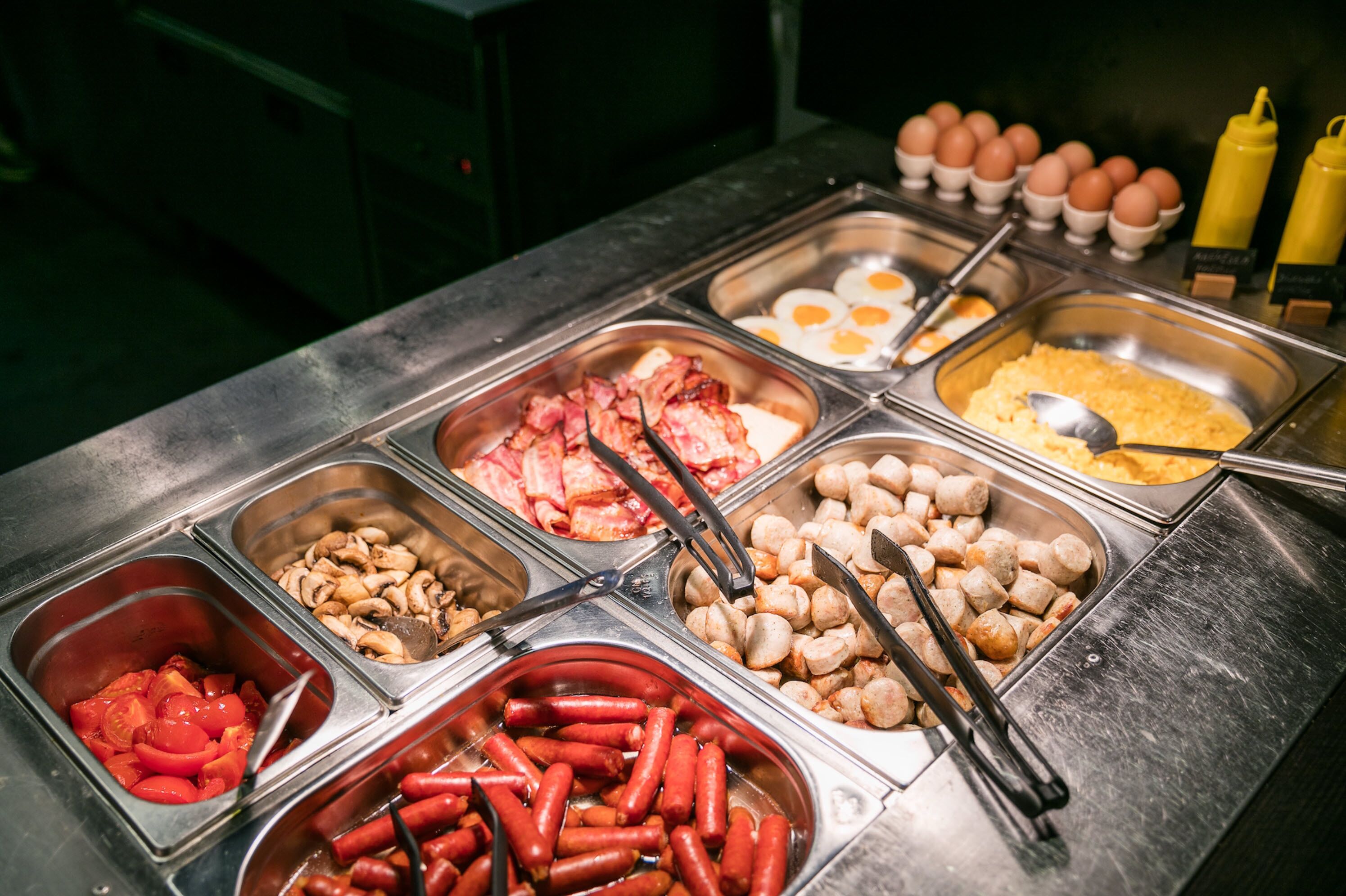 Buffet com diversas opções de comida, incluindo carnes, ovos e vegetais.