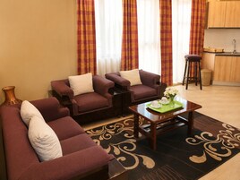 Sala de estar com sofá, mesa de centro e área de cozinha ao fundo.
