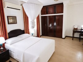 Quarto de hotel com cama, escrivaninha e guarda-roupa.