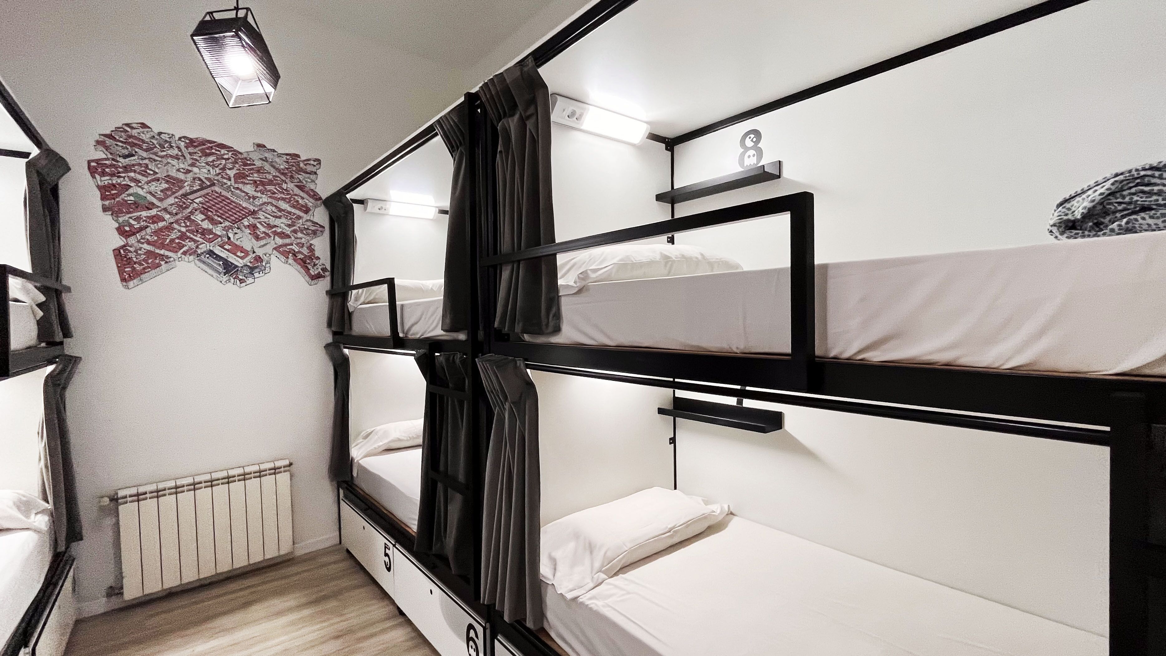 Quarto com beliche, arte de parede com vista urbana, radiador e luminária no teto.