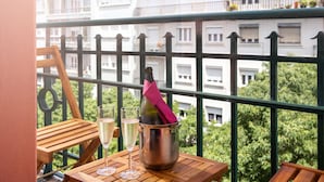 Uma varanda com uma mesa de madeira, dois copos de champanhe e uma garrafa de champanhe num balde de metal.
