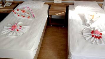 Duas camas de solteiro com roupa de cama branca e toalhas decorativas.