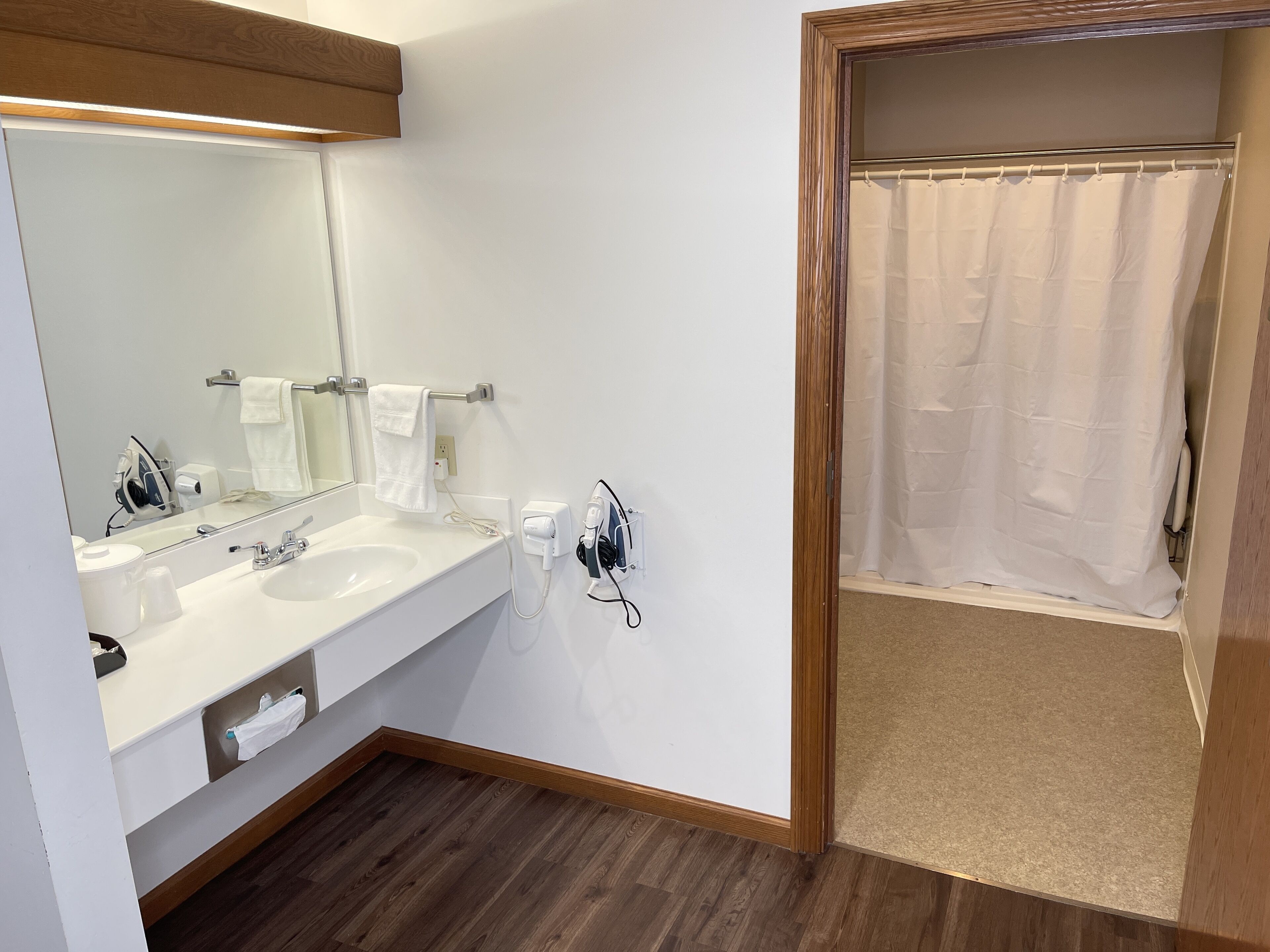 Casa de banho com duas pias, um espelho, um porta-toalhas e um cortina de chuveiro.