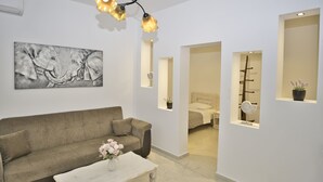 Uma sala de estar moderna com um sofá, uma mesa de centro com flores, uma pintura abstrata pendurada na parede e uma luminária de teto original.