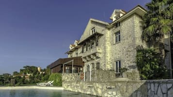 Um amplo edifício de pedra com piscina, boia e posto de salva-vidas.